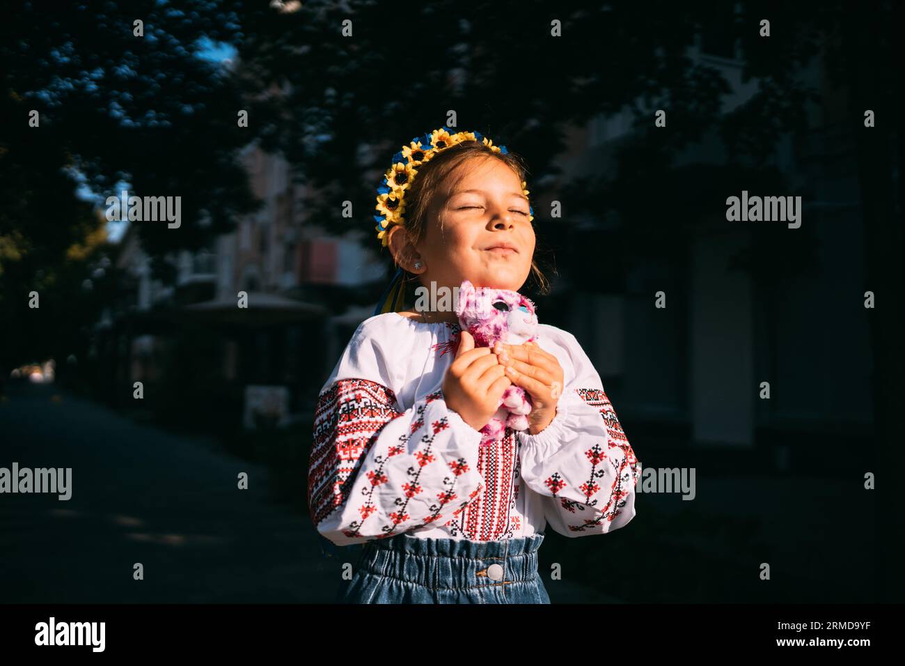 Child girl in Ukrainian traditional clothes and flower wreath is ...