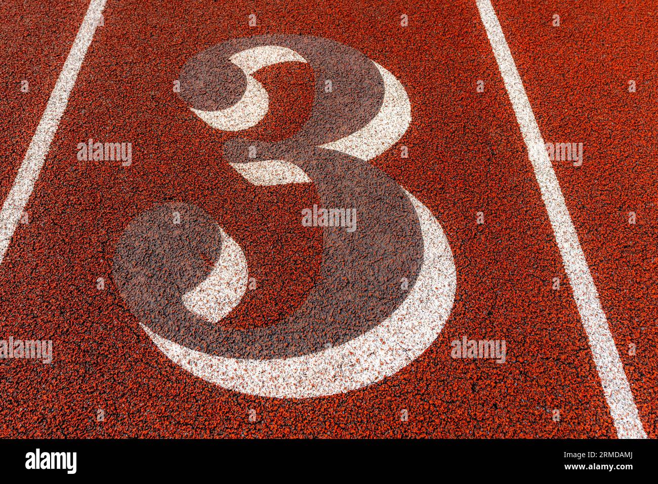 Close up lane number three 3, on a old red running track with white ...