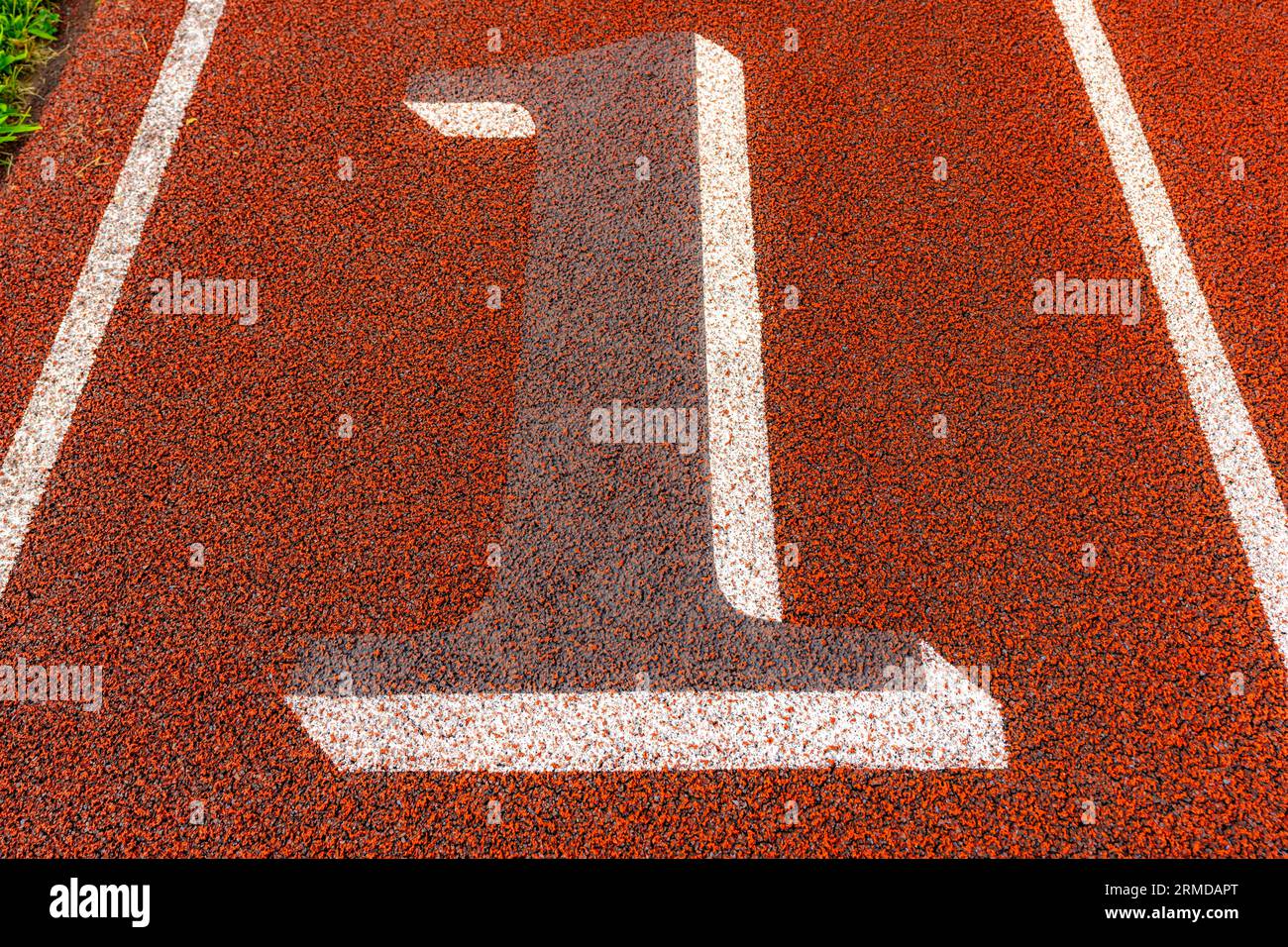 Close up lane number one, 1, on a old red running track with white lane ...