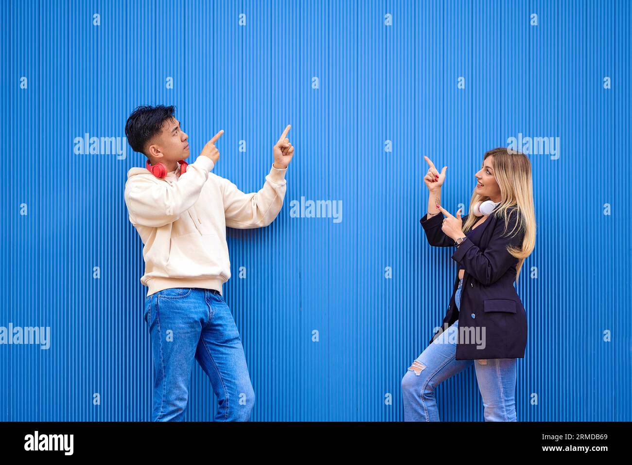 Multi-ethnic friends pointing at something while standing in front of a sheet metal wall Stock ...