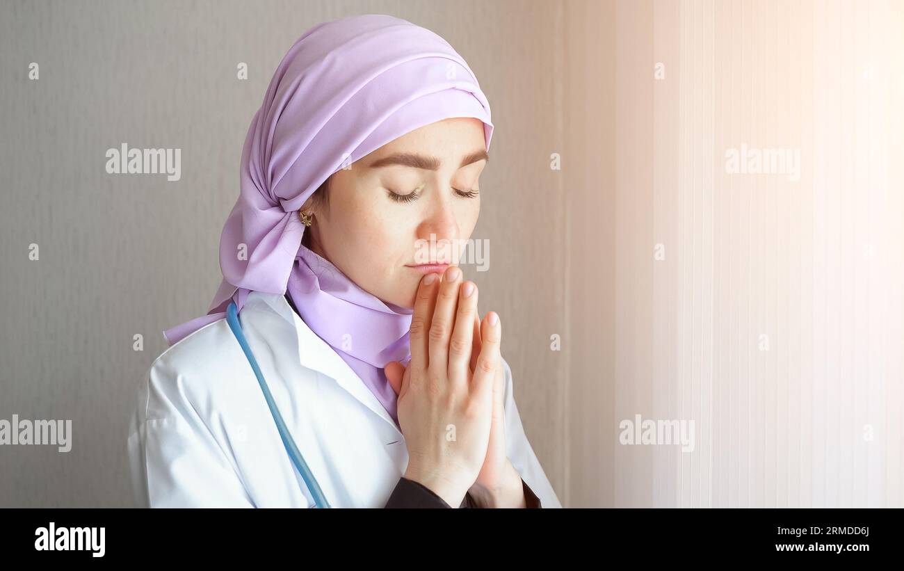 Muslim woman in hijab prays for quiet working day in clinic Stock Photo ...