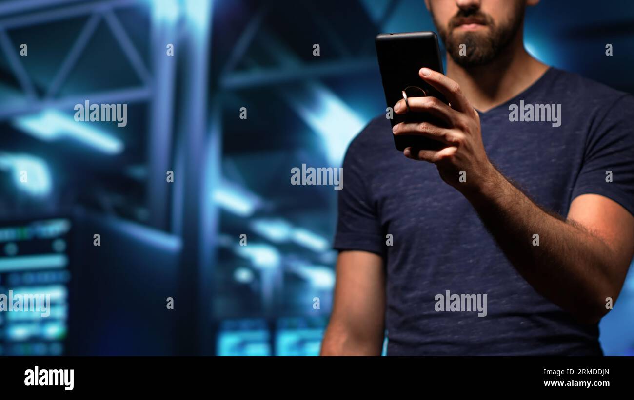 Man engineer working in server room using phone to check tech ...