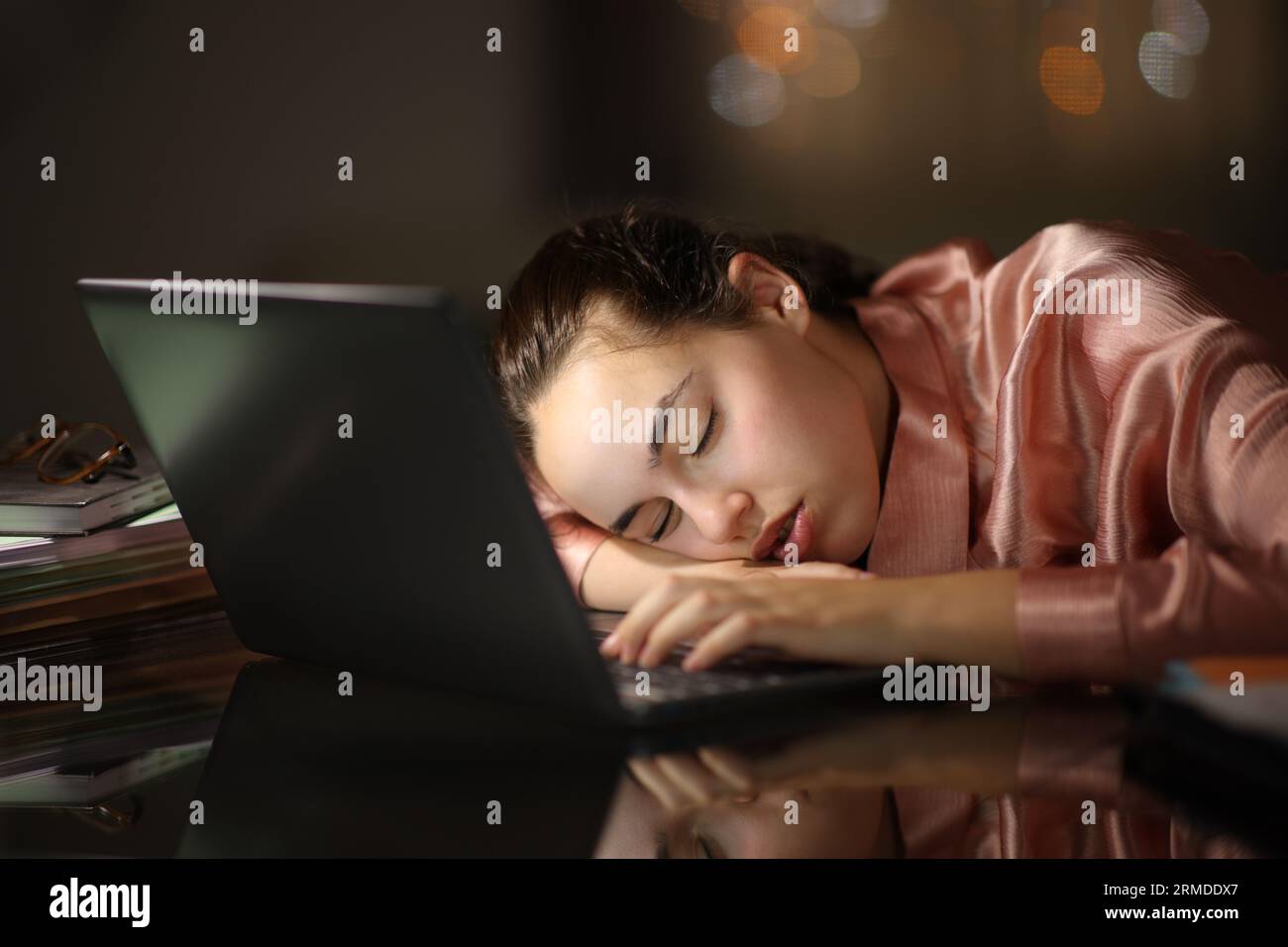 Overworked entrepreneur sleeping over laptop in the night at office or ...