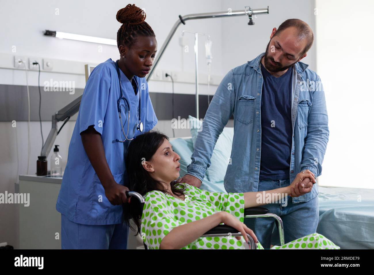 Gynecologist nurse helping pregnant woman to go to surgery in hospital ...