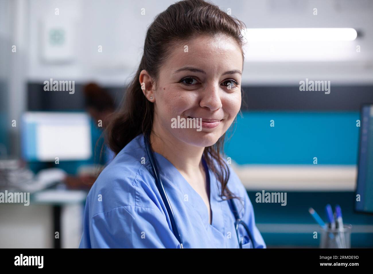 Cheerful caucasian nurse inside modern, clean, medical office, sitting ...