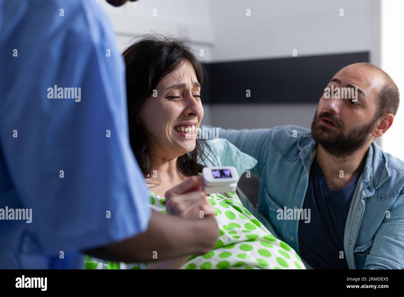 Pregnant woman holding hand of nurse and husband in hospital ward ...