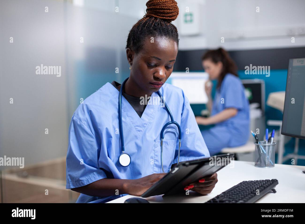 African american nurse working on digital touchscreen tablet in ...