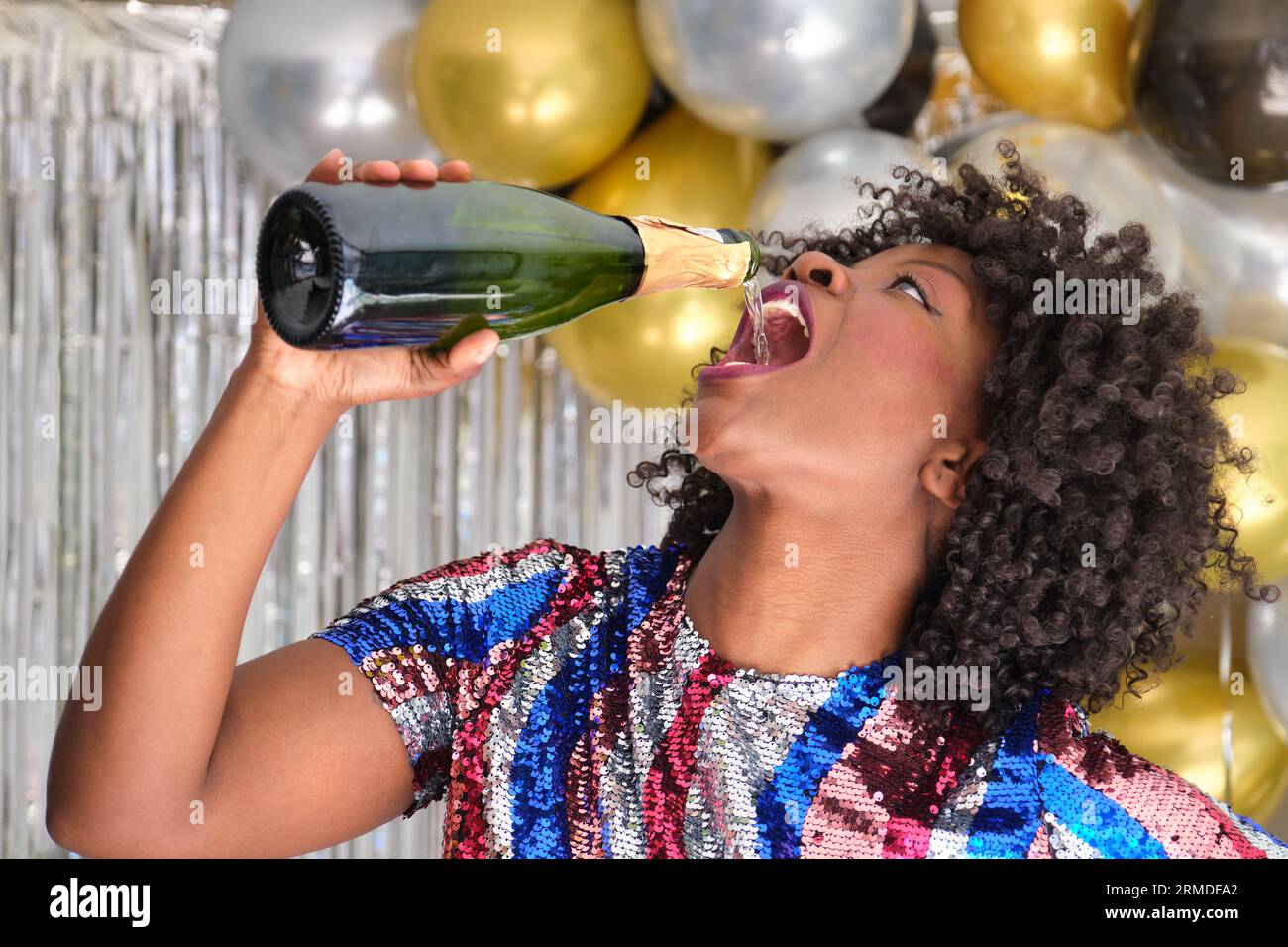 African woman drinking champagne from bottle celebrating New Year Stock ...