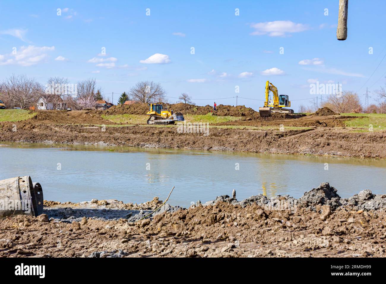 Excavators and bulldozer are moving earth to level, equates river coast ...