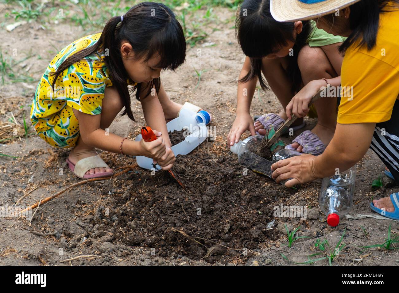 Little girl planting plants in pots from recycled water bottles in the ...