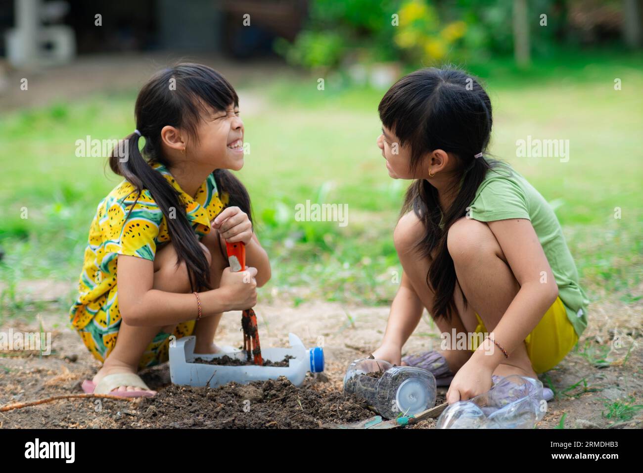 Little girl planting plants in pots from recycled water bottles in the ...