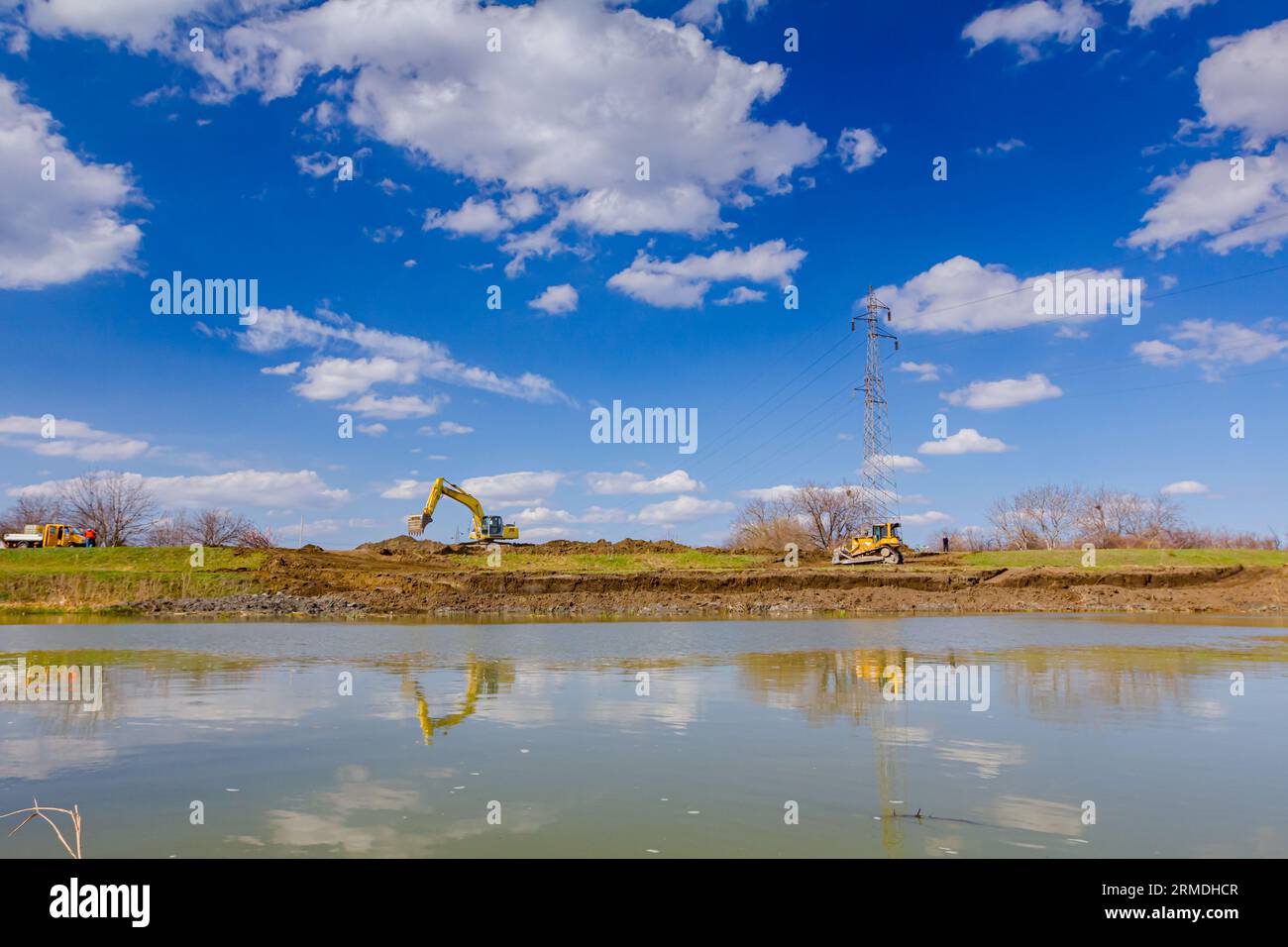 Excavators and bulldozer are moving earth to level, equates river coast ...