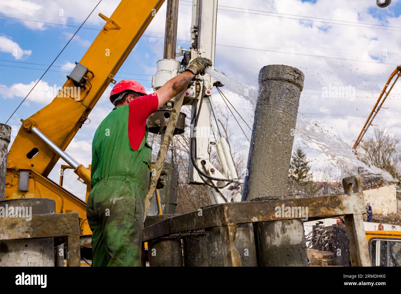 Rigger, worker with safety helmet is using hose to wash with water ...