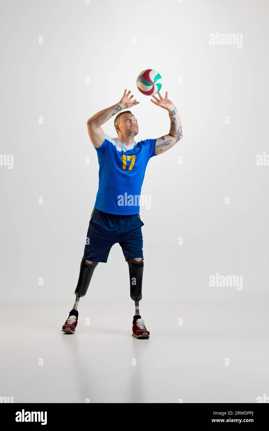 Confident young man with prosthetic legs disability in uniform hits ...