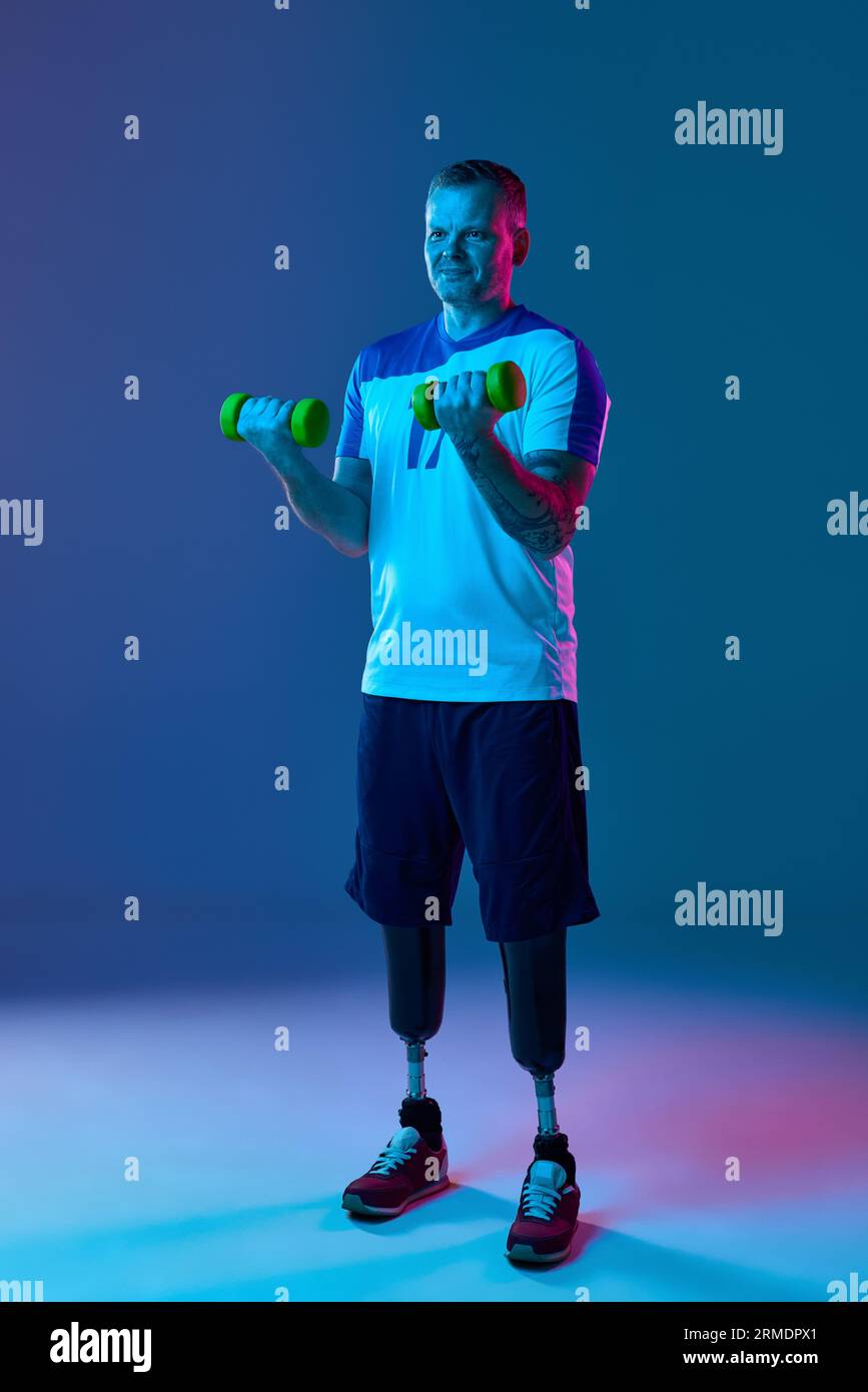 Young muscular man with prosthetic legs is training in gym with ...