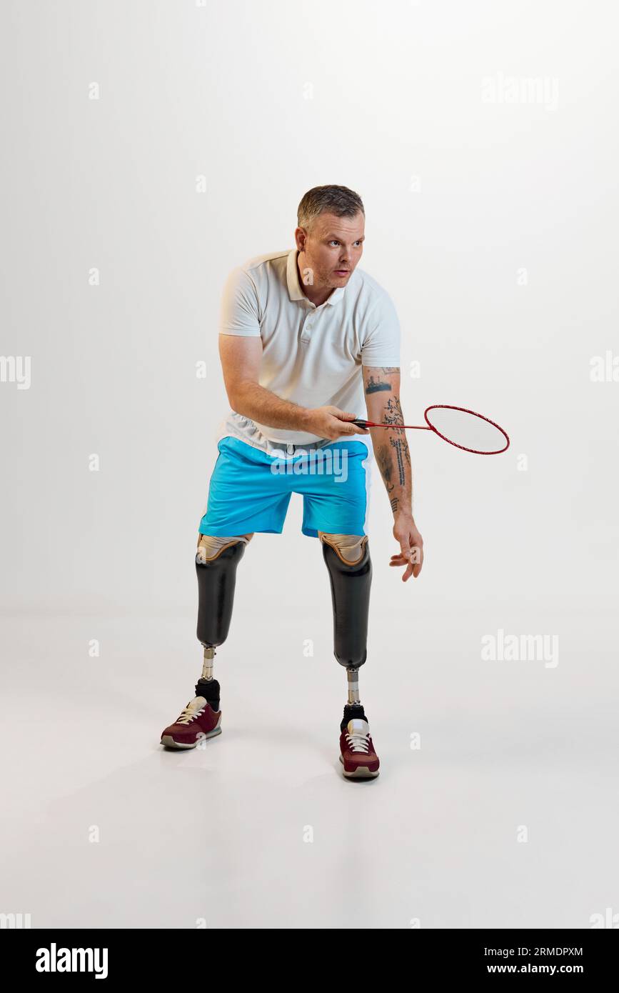 Full length of confident man with prosthesis play badminton indoors and ...