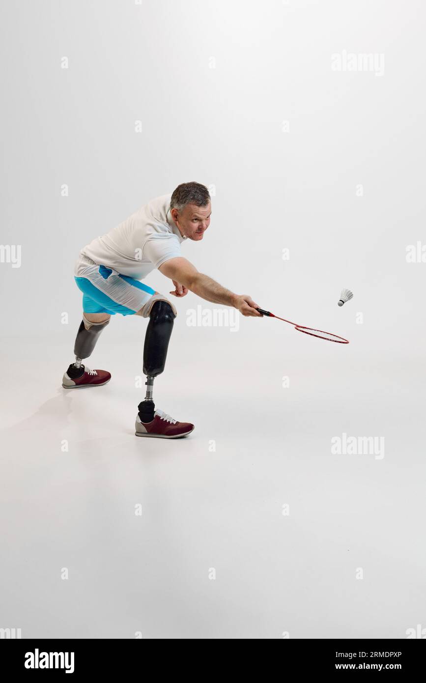 Full length of confident man with prosthesis play badminton, catching ...