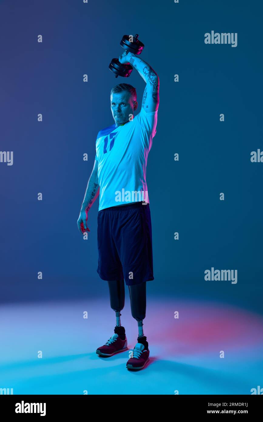 Confident young muscular man prosthetic legs shakes muscles of hands ...