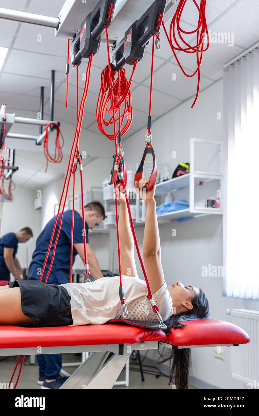 Female patient hanging on suspensions at rehabilitation center Stock ...