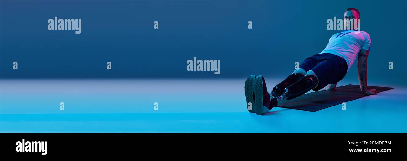 Confident man in sport uniform with prosthetic legs doing plank in ...
