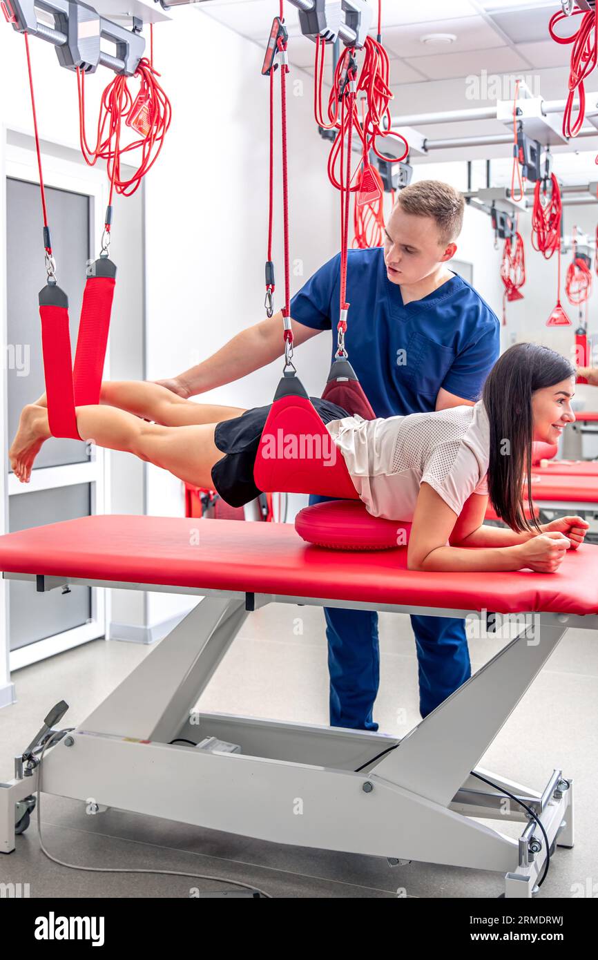 A young female is doing exercises with special ropes in rehabilitation ...
