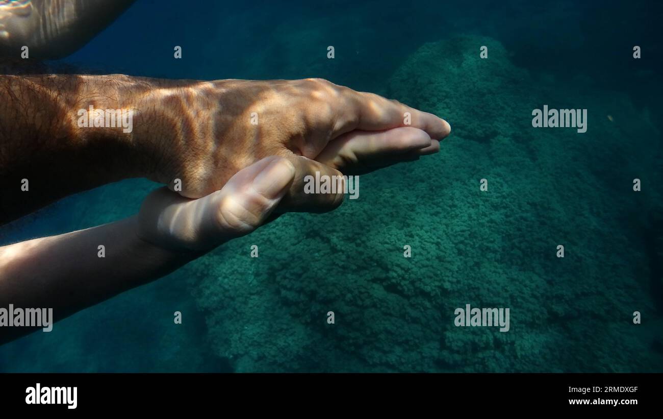 A man and woman crossed human hands underwater detail Stock Photo - Alamy