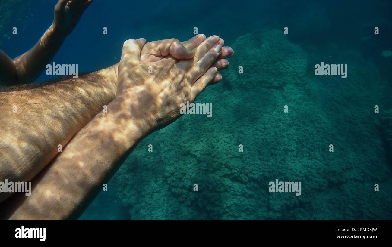 A man and woman crossed human hands underwater detail Stock Photo - Alamy