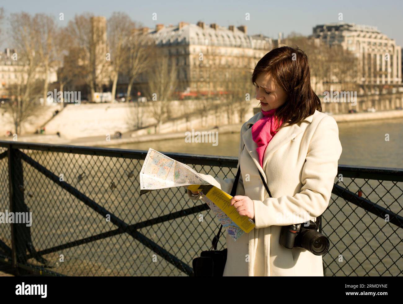 Getting lost in Paris. Beautiful woman with map on a Parisian bridge ...