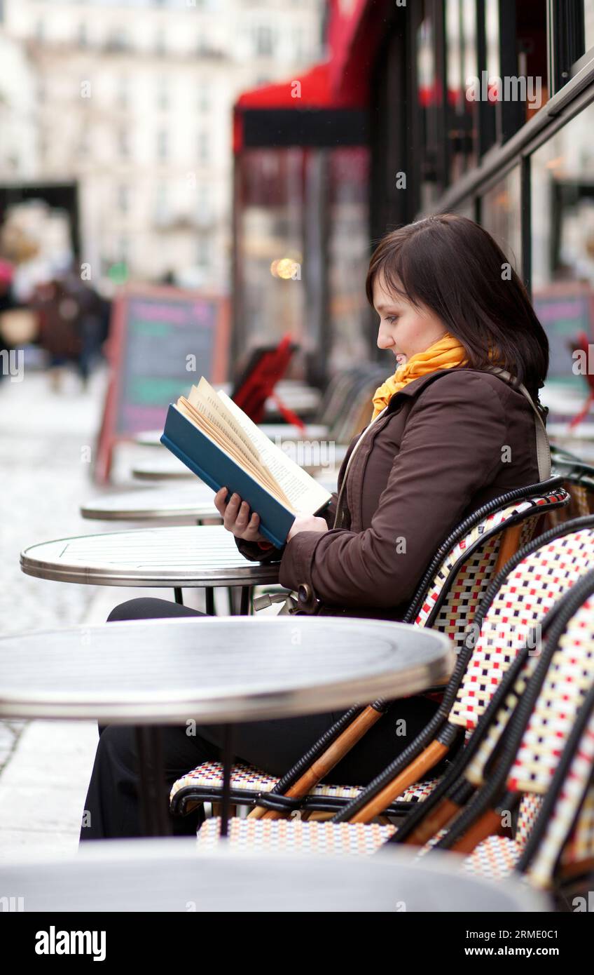 Beautiful young girl reading a book in Parisian street cafe Stock Photo ...