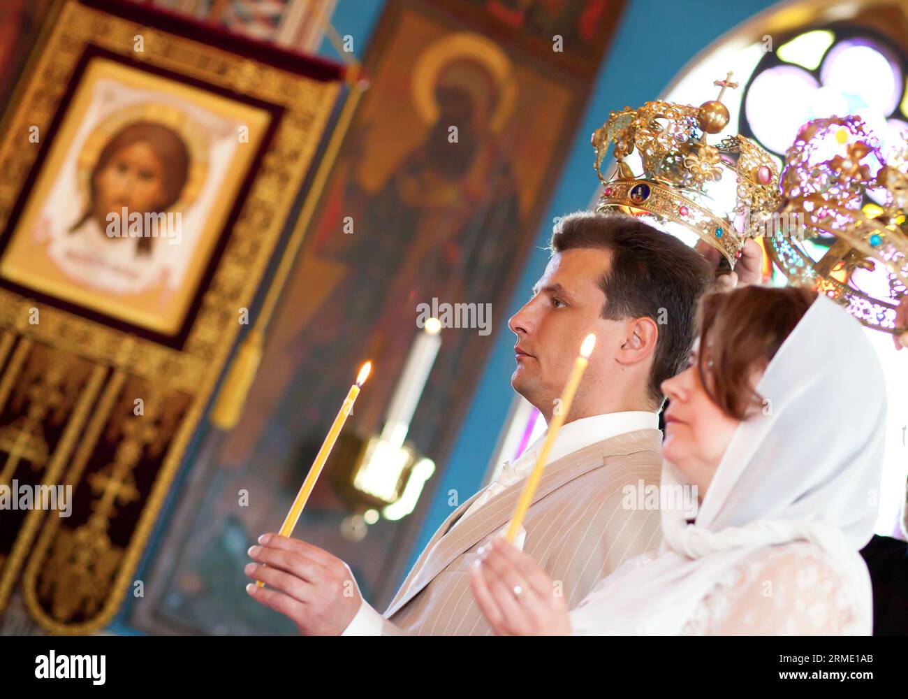 Bride and groom during orthodox wedding ceremony with crowns above ...