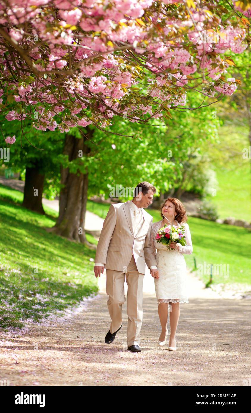 Beautiful newlywed couple having a stroll in park at spring Stock Photo ...