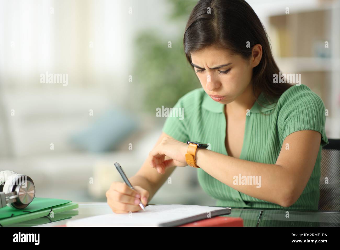 Frustated student checking smartwatch studying at home Stock Photo - Alamy