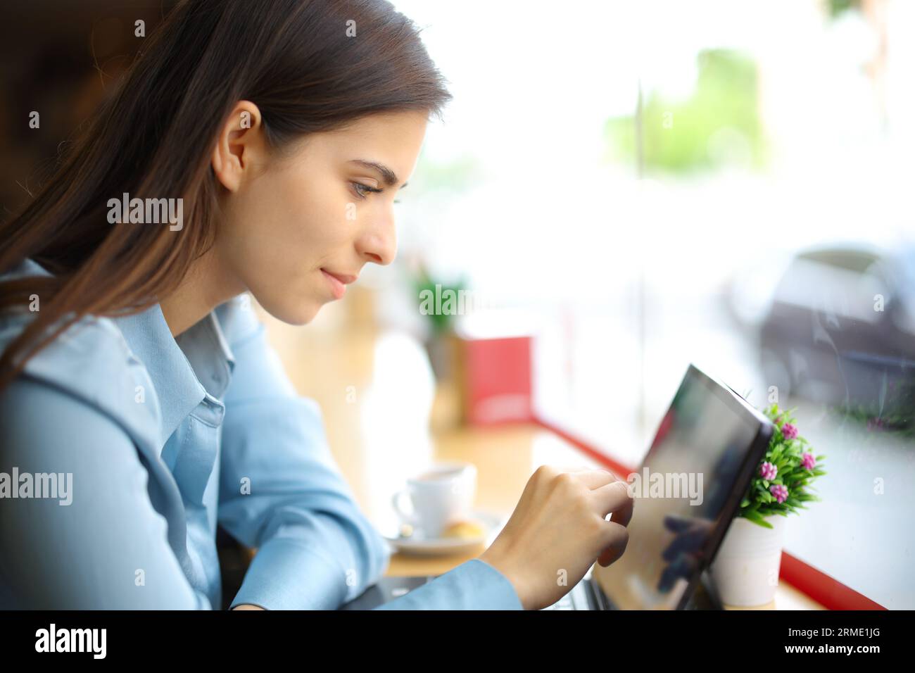 Side view portrait of a woman in a coffee shop using tablet alone Stock ...