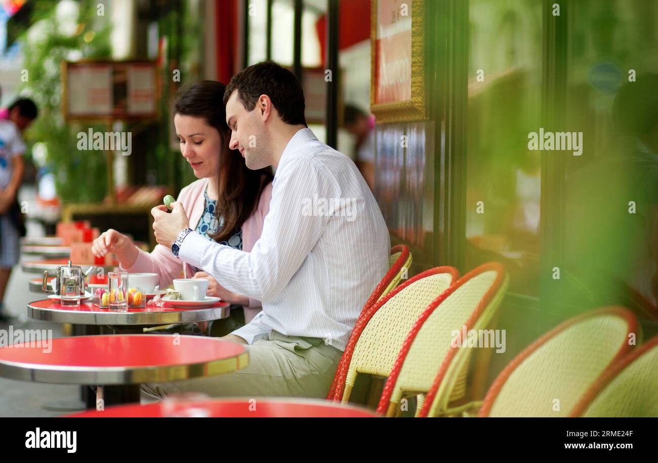 Happy couple eating macaroons in a Parisian outdoor cafe Stock Photo ...