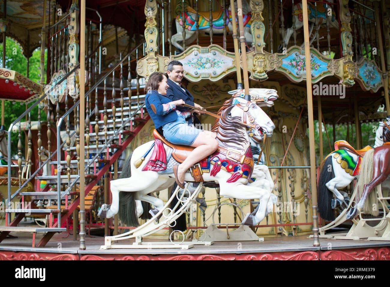 Couple having fun on merry-go-round Stock Photo - Alamy