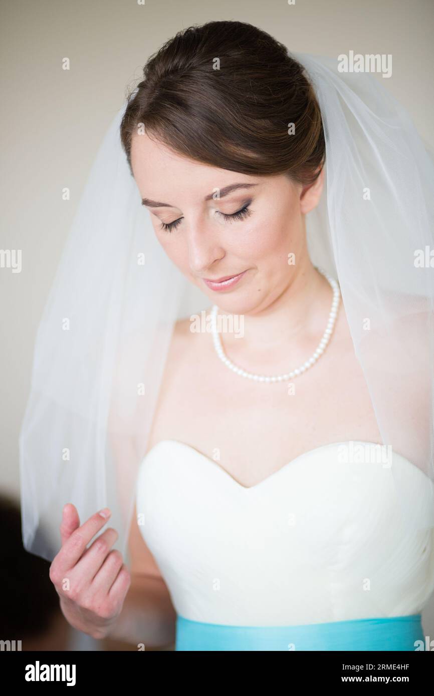 Beautiful young bride getting dressed on the wedding day Stock Photo ...