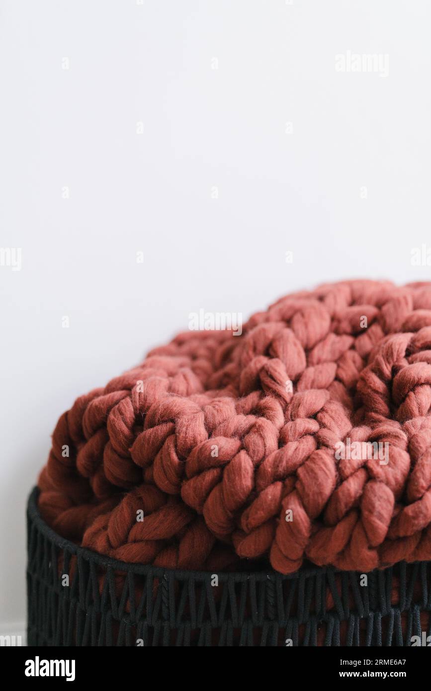 Rust chunky knit blanket in black basket by white wall Stock Photo - Alamy