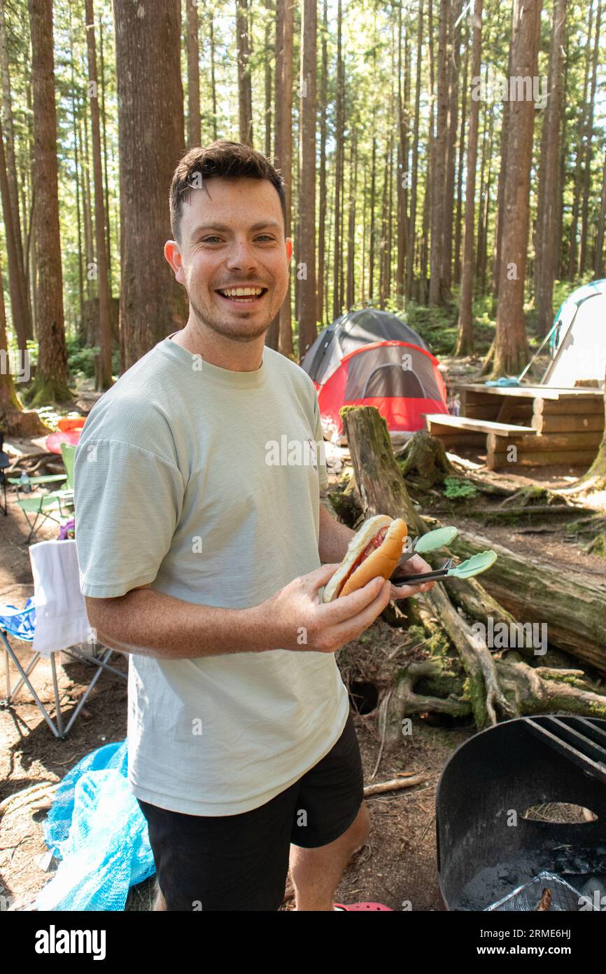 Man enjoying hot dog while grilling at campsite BBQ Stock Photo - Alamy