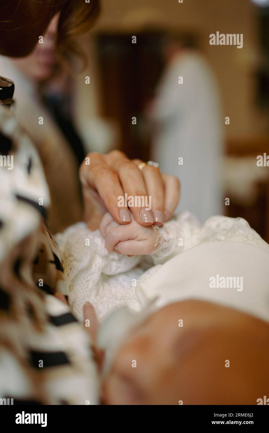 Mother holds baby's hand during christening and baptism ceremony Stock ...
