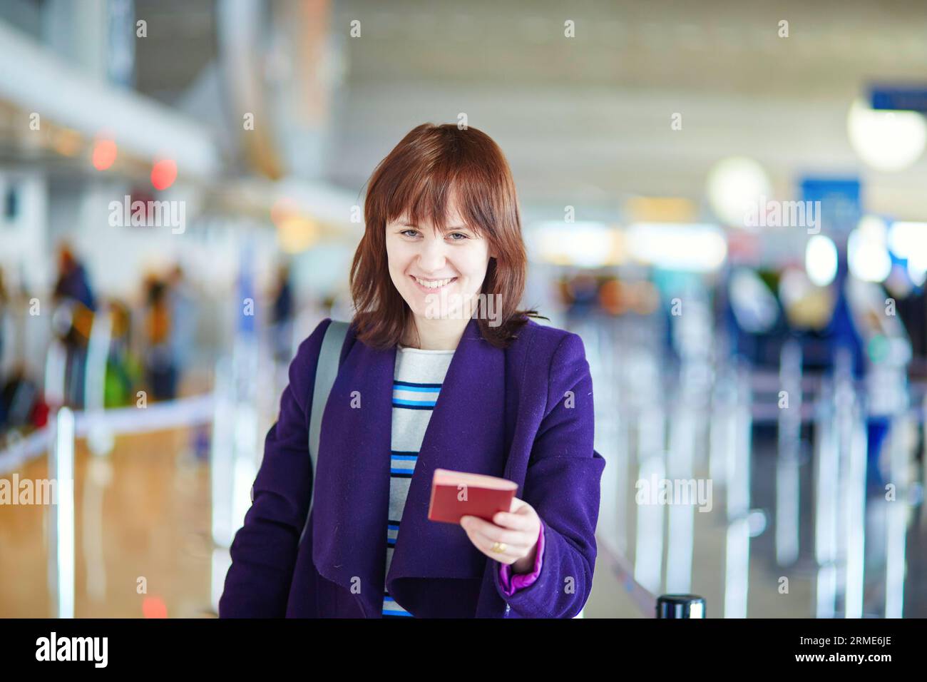 Beautiful young female passenger at check-in counter in the airport ...