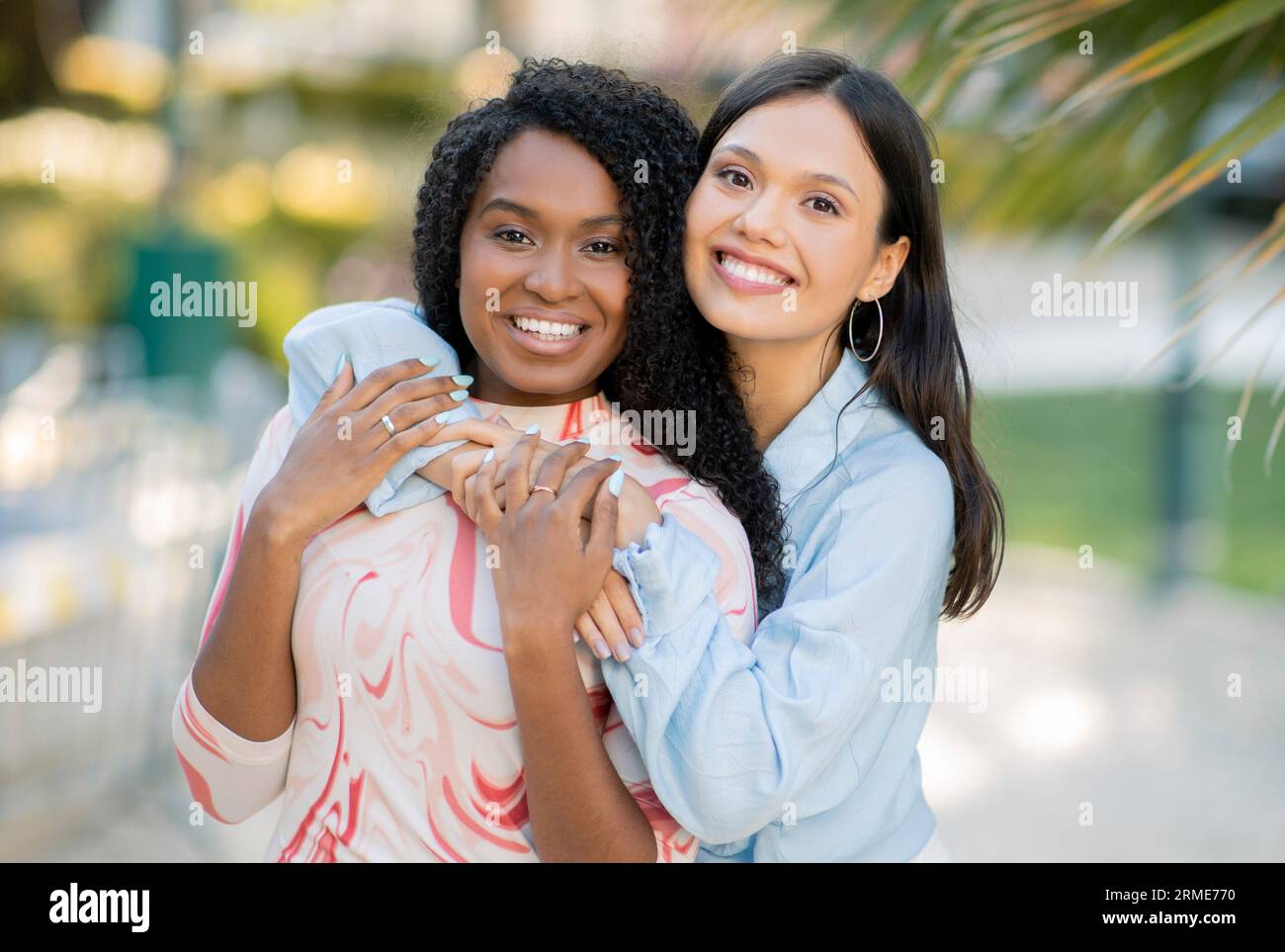 Portrait of two multiracial female friends hugging and posing together ...