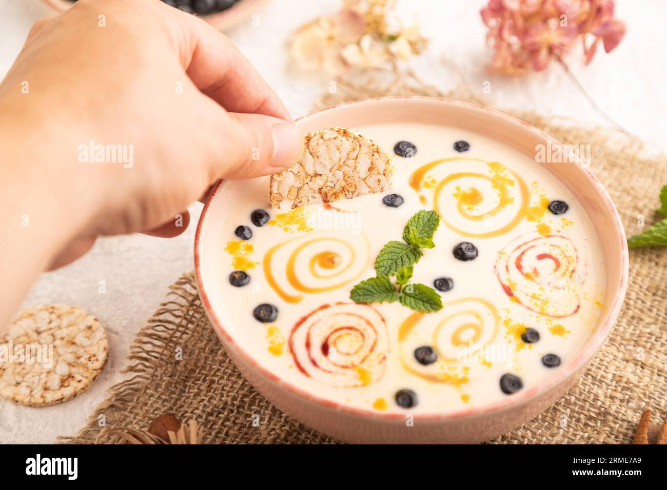Yoghurt with bilberry and caramel in ceramic bowl on gray concrete ...