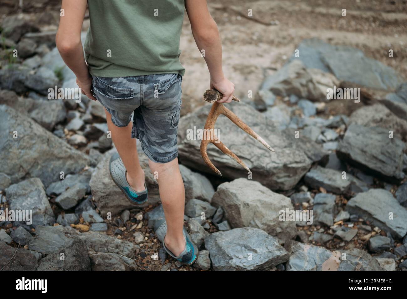 Boy carrying a deer shed antler across rocky landscape Stock Photo - Alamy