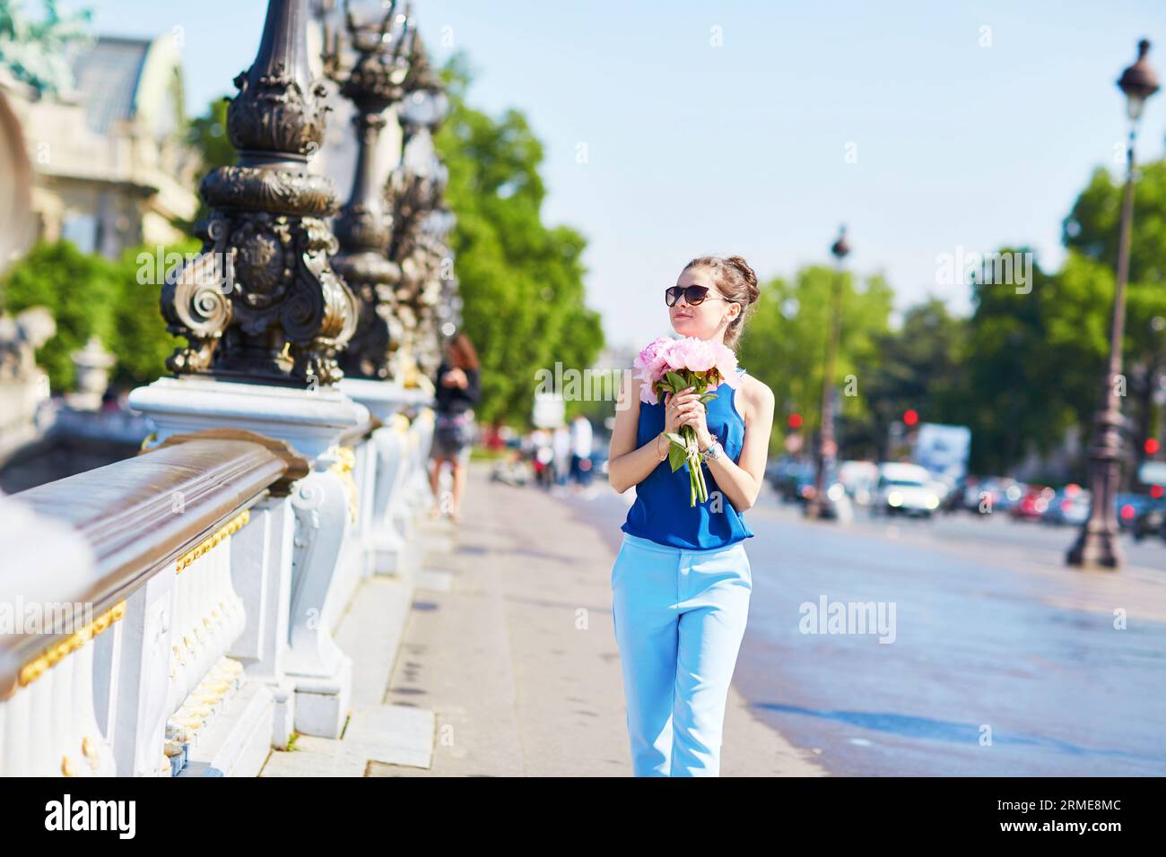 Beautiful young Parisian woman in blue tube top with bunch of pink ...