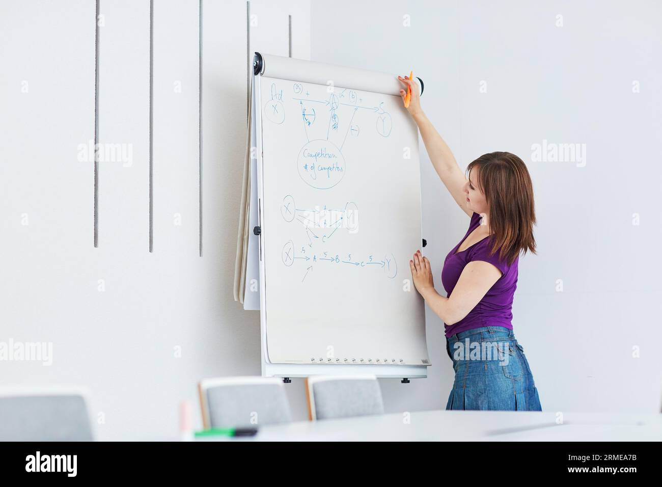 Pretty young student or business woman writing on a paper board during ...