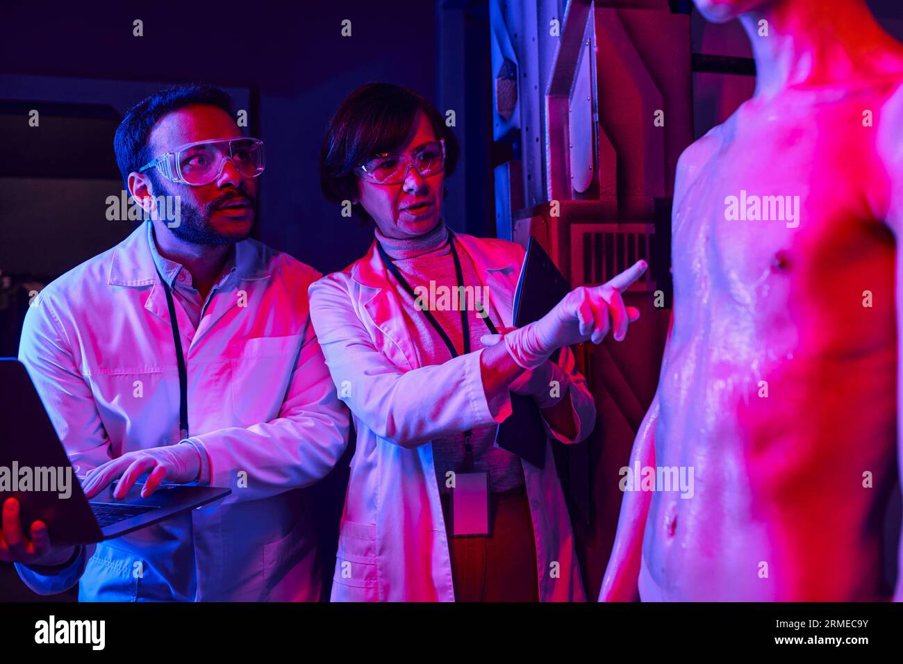 indian scientist with laptop near colleague pointing at unknown ...