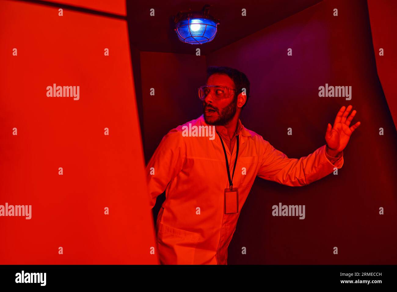 unknown phenomenon, scared indian scientist looking away in red neon ...