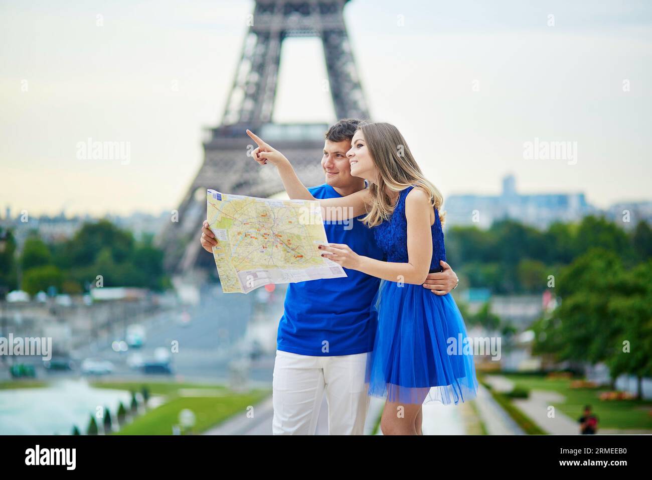 Beautiful young dating couple in Paris near the Eiffel tower using map ...