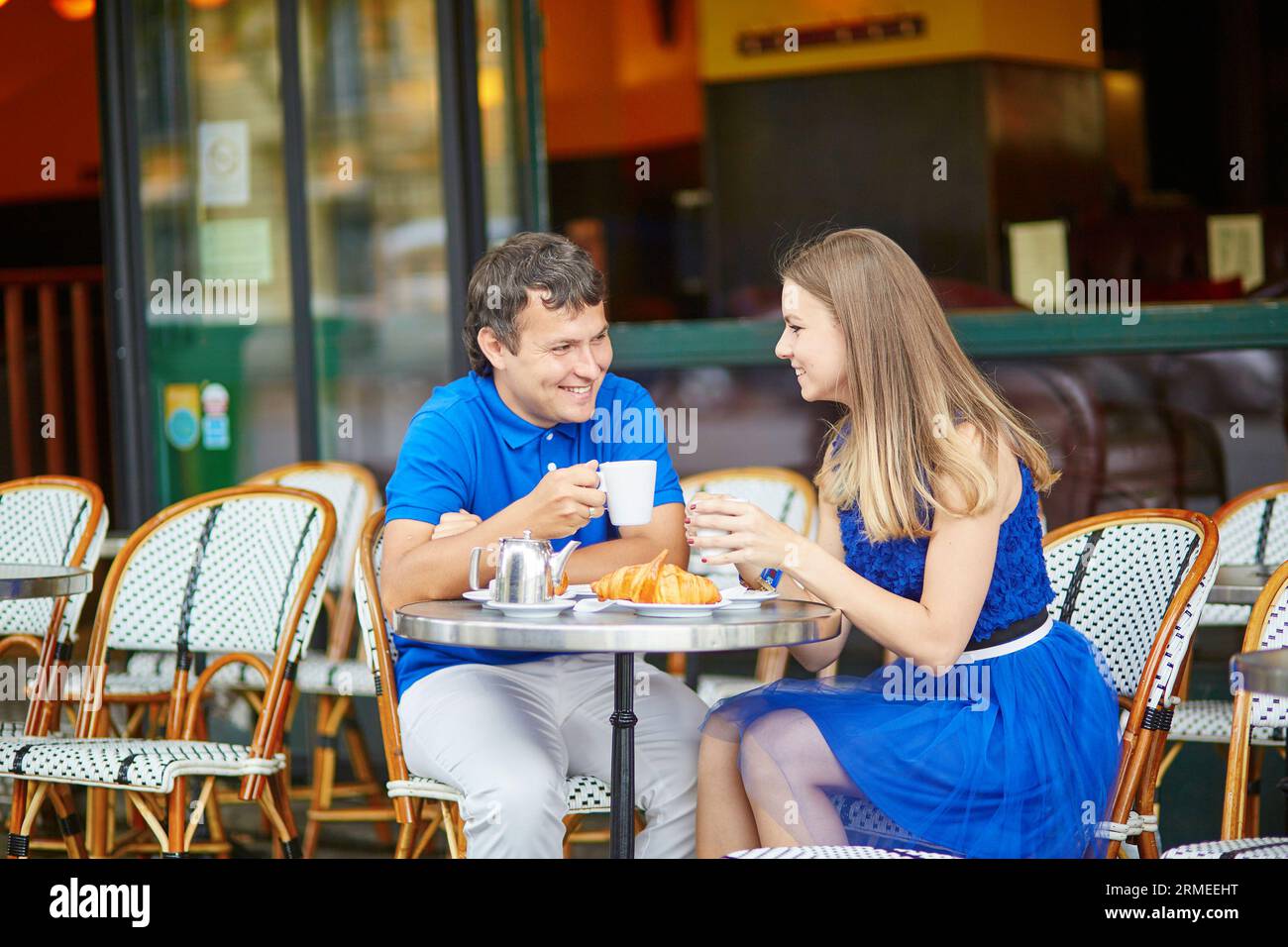 Beautiful young couple of tourists drinking coffee and eating ...