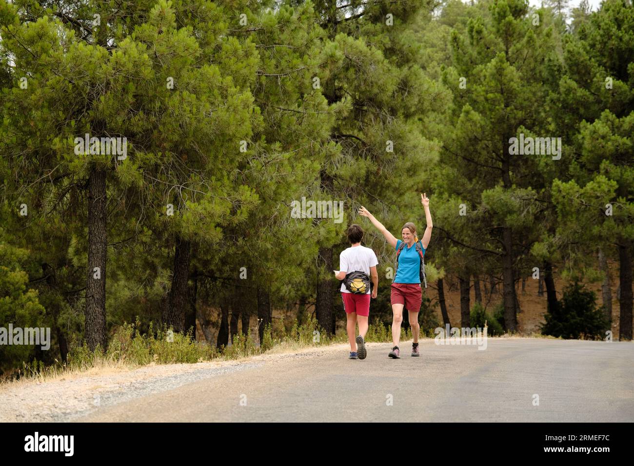 Happy female and anonymous boy walking on asphalt road Stock Photo - Alamy